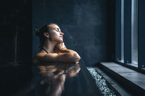 Mulher Jovem E Atraente Em Um Maiô Preto Está Relaxando Na Piscina