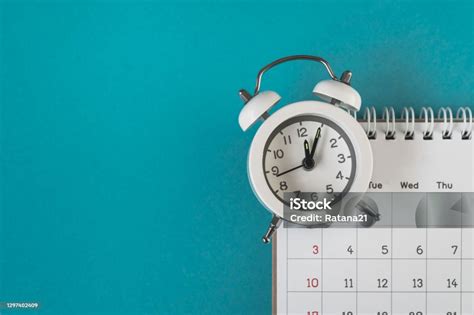 복사 공간 비즈니스 미팅 일정 여행 계획 또는 프로젝트 이정표 및 미리 알림 개념이 있는 그런지 블루 배경이 있는 흐린 달력의 흰색 아날로그 알람 시계 수첩에 대한 스톡