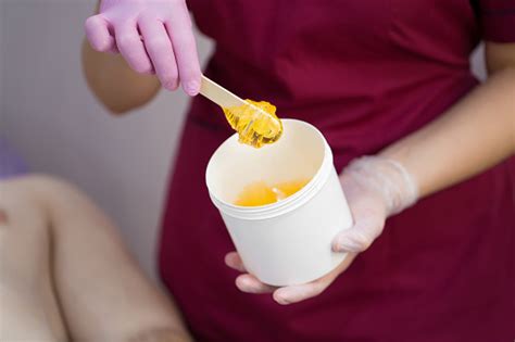 미용사는 항아리에서 설탕 페이스트를 취합니다 으르렁거리고 주걱으로 용기밖으로 설탕 페이스트 설탕 을 위한 설탕 페이스트