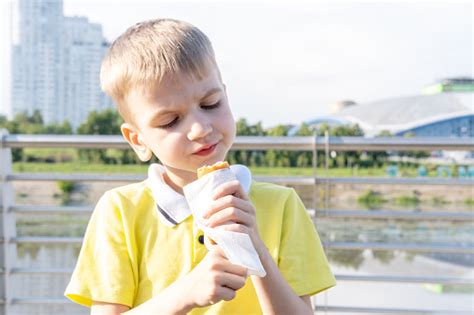 배고픈 아이는 여름에 해변에서 길거리 음식을 먹는다 막대기에 튀긴 소시지를 먹는 작은 감정적 인 소년 가공육에 대한 스톡 사진 및 기타 이미지 Istock