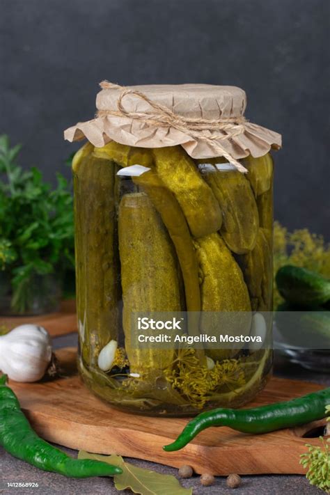 회색 배경에 나무 판에 유리 항아리에 칠리 고추 마늘 및 딜을 곁들인 수제 절인 오이 가득 찬에 대한 스톡 사진 및 기타 이미지