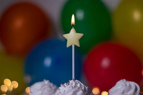 노란 별 모양의 촛불이 달린 축제 컵케이크 배경에 여러 가지 색상의 풍선과 조명 파티 생일 개념 공간을 복사합니다 고독 부정적인