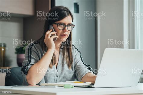 그녀의 노트북 컴퓨터와 휴대 전화에서 집에서 일하는 아름다운 비즈니스 여성 노트북에 대한 스톡 사진 및 기타 이미지 노트북 말하기 일함 Istock