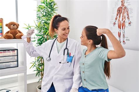 Woman And Girl Doctor And Patient Doing Power Gesture At Clinic Stock