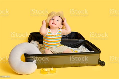 아기 유아 소년은 옷 스튜디오 노란색 배경이있는 여행 가방 안에 앉아 있습니다 어린이는 휴가 여행 복사 공간을 위해 수하물을 포장하는 동안 큰 가방에서 놀고 있습니다 어린이