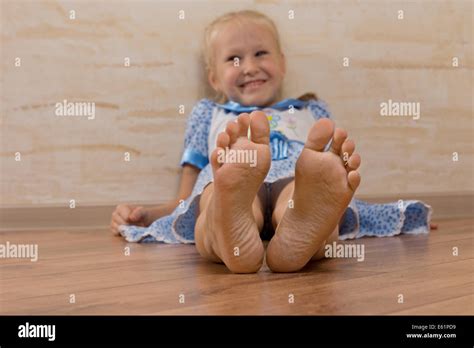Smiling Young Girl Showing Feet On Camera Isolated On Wooden Brown