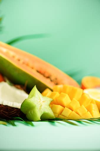 청록색 바탕에 이국적인 과일의 구색입니다 해독 채식주의 음식 여름 개념입니다 파파야 망고 파인애플 Carambola 드래곤 과일 키 위 오렌지 멜론 코코넛 팜 잎에 석 회