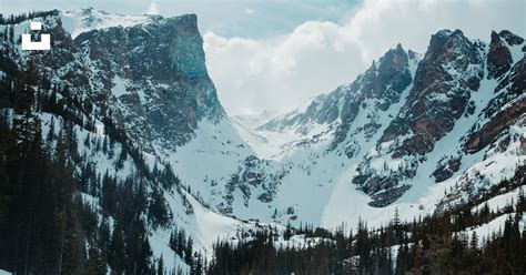 낮에는 흰 구름과 푸른 하늘 아래 산 근처의 눈 덮인 들판과 나무 사진 Unsplash의 무료 산 이미지