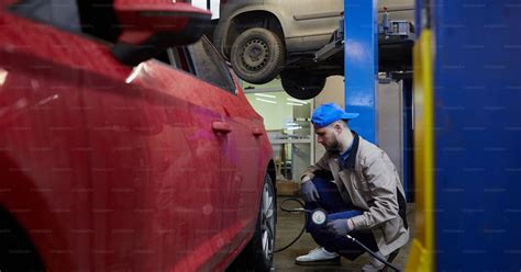타이어 공기압 게이지를 사용하여 자동차 바퀴 앞에 앉아 있는 전문 수리공의 수평 측면도 샷 사진 Unsplash의 남자 이미지