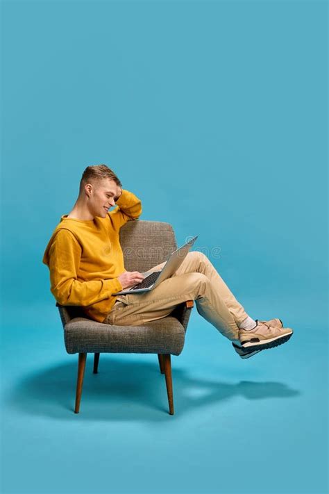Man Sitting On Chair Working On Laptop Leaning Back With Relaxed Posture Focusing Intently On