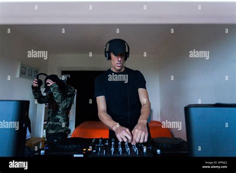 Cheerful Adult Male And Female Djs In Casual Clothes Spinning Buttons On Mixing Console While