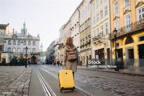 가을에 고대 유럽 거리를 걷는 여행 가방을 든 아름다운 쾌활한 여자 여행 가방에 대한 스톡 사진 및 기타 이미지 여행 가방 여행 주제 여행 개념 Istock