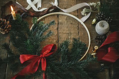 메리 크리스마스와 해피 홀리데이 촛불 리본 솔방울이 있는 소박한 나무 테이블에 전나무 가지와 빨간 활이 있는 현대 크리스마스 화환 분위기 있는 분위기 있는 이미지