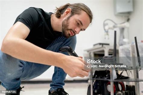 똑똑한 백인 전문 엔지니어 또는 기술자 노동자 남자 확인 및 유지 보수 공장 작업장의 방에 바닥에 놓인 작은 로봇 기계 20 24세에 대한 스톡 사진 및 기타 이미지