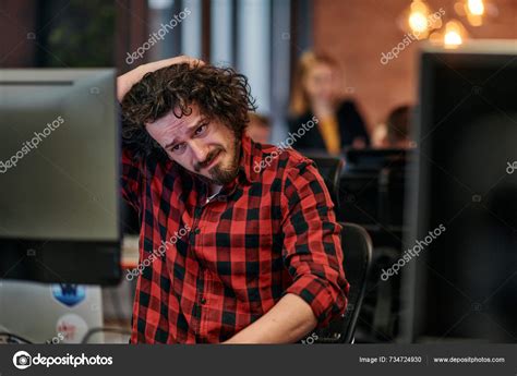 frustrated programmer messy hair sits staring his computer monitor look