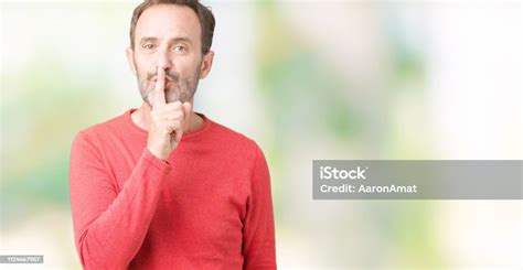 잘생긴 중간 나이 노인의 수석 남자 입술에 손가락으로 조용 하 게 묻는 고립 된 배경 위에 겨울 스웨터를 입고 침묵 및 비밀 개념입니다 남자에 대한 스톡 사진 및 기타