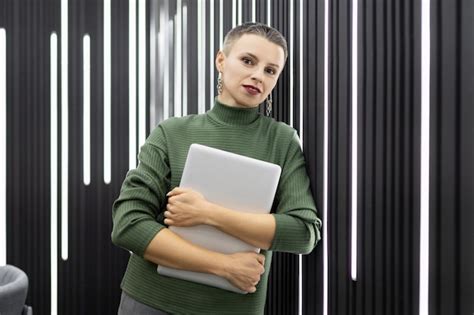 Premium Photo Woman Programmer With A Laptop In Her Hands Against The Background Of A Wall In