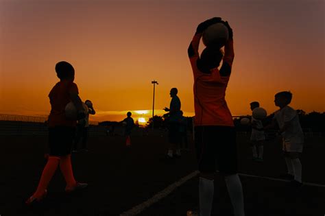 코치와 축구 골키퍼 훈련 세션에 학교 소년 트레이너와 연습에 골키퍼 어린 소년 축구 골의 그룹 절약 기술을 향상 경기장의 일몰 Championship에 대한 스톡 사진 및