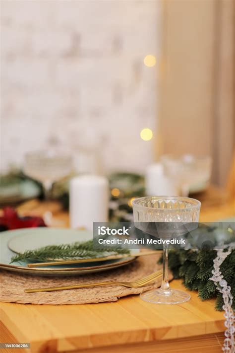 축제 크리스마스와 새해 테이블 설정 전나무 가지 화환 및 양초로 장식 된 식당 짚 냅킨에 빈 접시 금 칼 붙이 및 나무 테이블에 크리스탈 음료 잔 0명에 대한 스톡 사진 및