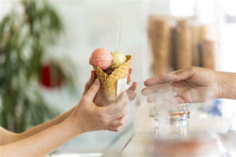a man is serving an ice cream cone of various flavors to a woman stock