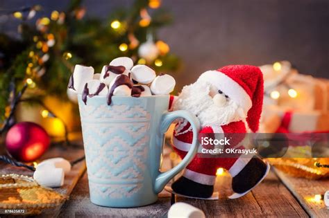 장식용 산타 클로스와 크리스마스 트리 조명 및 오래 된 나무판에 장식 축제 어두운 배경에 마 시 멜로 코코아 한 잔을 들고