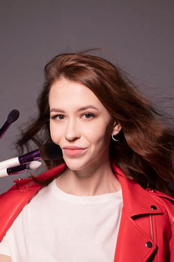 회색 벽 배경에 고립 된 메이크업 브러시와 빨간 가죽 재킷에 매력적인 갈색 머리 여자 전문 메이크업 아티스트 가죽에 대한 스톡 사진 및 기타 이미지 Istock