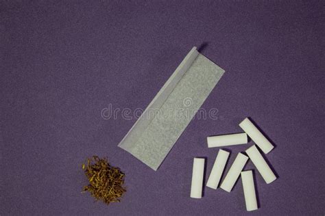 pile of dry tobacco paper and filters on a purple background finely