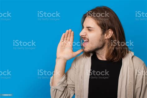 수염과 긴 머리를 가진 백인 남자는 자유 공간 광고 뭔가와 파란색 스튜디오 벽에 비명을 지르고있다 비명에 대한 스톡 사진 및 기타 이미지 Istock