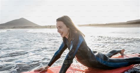 잠수복을 입은 젊은 여자는 서핑 보드에서 물의 흐름을 잡고 일몰 동안 물결 모양의 바다에서 서핑을 합니다 수상 스포츠와 활동적인 라이프 스타일 개념 사진