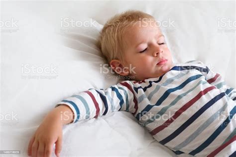 하얀 부드러운 담요 위에서 자고 있는 어린 아이 3살짜리 아이들은 아늑한 침실에서 혼자 잔다 부드러운 섬유 졸린 금발 머리 아기