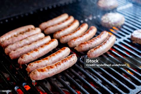 그릴에 소시지 그 위에 연기와 함께 휴대용 바베큐에 구운 돼지 고기 소시지 와 함께 한 소시지는 여름 피크닉에 집게 한 켤레에 설정 되 고 그릴 고기와 불의 가까이 0명에