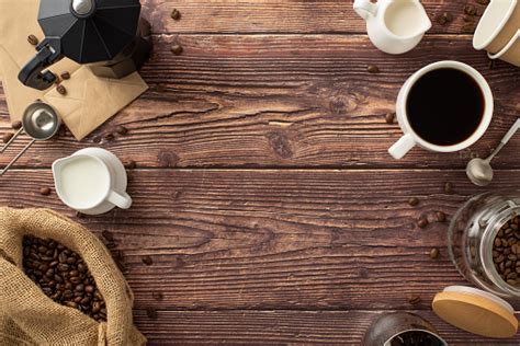 커피 데이의 기쁨 삼베 가방 에스프레소 테이크아웃 종이컵 우유 및 크림 항아리 숟가락 나무 테이블 위의 주전자에 담긴 커피