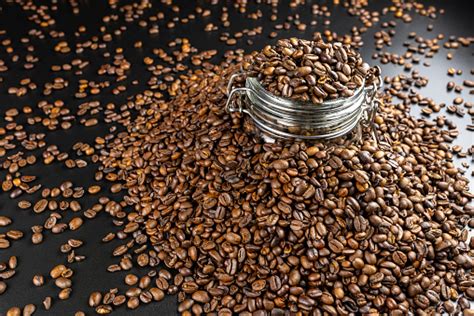 신선하고 구운 커피 원두는 검은 탁자 위에 서있는 투명한 투명한 항아리에 커피 콩 더미가 흩어져 있습니다 0명에 대한 스톡 사진 및 기타 이미지 Istock