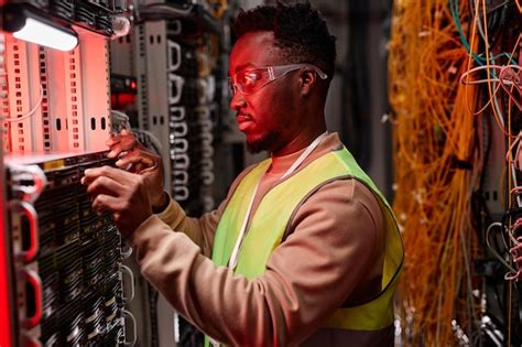 Premium Photo Network Technician Inspecting Servers In Data Center Red Neon Light