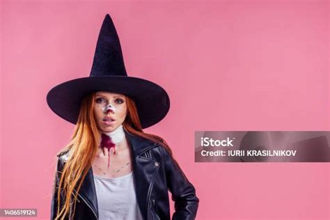 거대한 마녀 모자와 검은 가죽 재킷으로 옷을 입은 빨간 머리 생강 소녀 짜증나는 피가 코와 목 붕대의 골절을 구성합니다 10월에