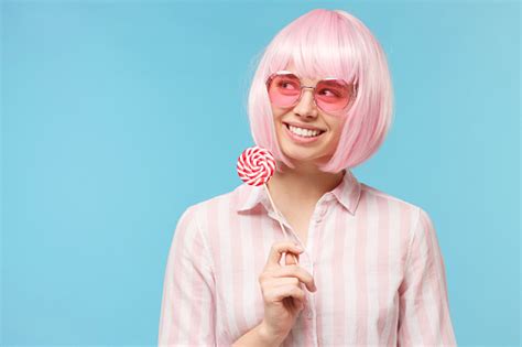 읽기와 흰색 롤리팝을 들고 있는 어린 행복한 소녀는 카피 공간으로 파란 배경에 고립 된 미소로 멀리 쳐다 보며 20 29세에