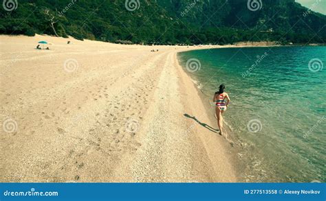 A Beautiful Woman In Striped Swimsuit Running On The Beach Aerial