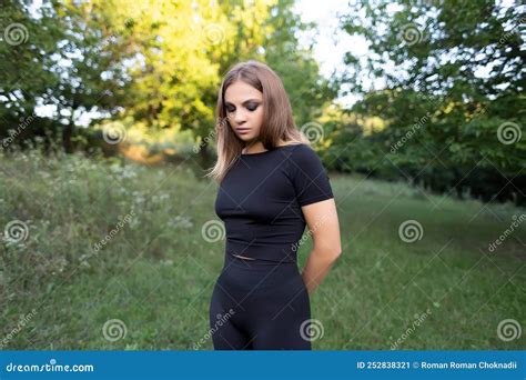 A Girl In A Fitness Model Is Standing In The Park Lowered Her Eyes Down