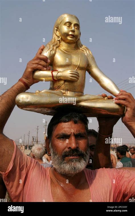 A Sadhu, or Hindu holy man, carries an idol of Hindu Giod Chandra, at the Sangam, the confluence ...