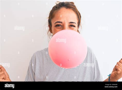 Young Redhead Woman Chewing Gum And Blowing Hair Bubble Over White