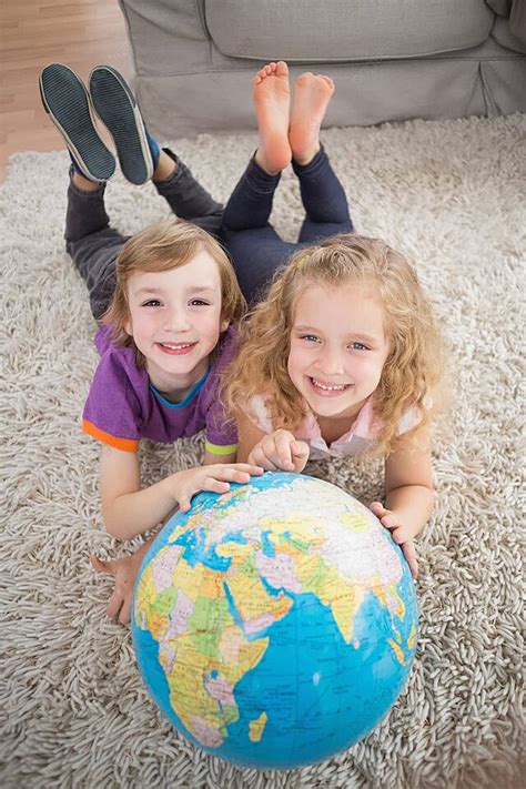 Siblings Exploring The World With A Globe On A Cozy Rug Photo Background And Picture For Free