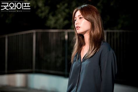 A Woman Standing In Front Of A Fence At Night With Her Head Turned To The Side