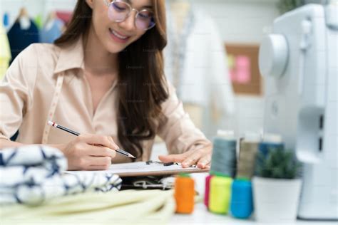 아시아의 아름다운 재단사 여자가 재봉 아틀리에에서 옷을 입고 있다 매력적인 여성 패션 디자이너 양장점 디자인 드로잉 및 워크샵