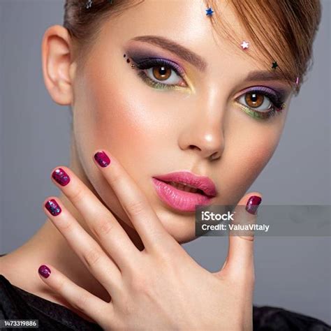 밝은 화장을 한 아름다운 여자의 초상화 보라색 눈 화장으로 여성 얼굴을 클로즈업합니다 얼굴 근처에 보라색 손톱을 가진 예쁘고 섹시한 소녀 짧은 매끄러운 머리를 가진 세련된