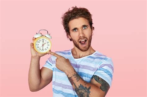 Premium Photo Astonished Man Pointing At Alarm Clock