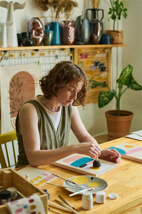 워크숍에서 새로운 추상 회화 작업을 하는 동안 종이에 색상을 적용하기 위해 스폰지를 사용하는 캐주얼웨어를 입은 창의적인 여성 예술가 사진 Unsplash의 러시아 이미지