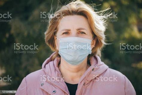 의료 마스크에 여자입니다 깊게 숨을 들이쉬고 야외에서 녹색 배경의 카메라를 바라볼 수 있습니다 의료 및 의료 개념 갈색 머리에