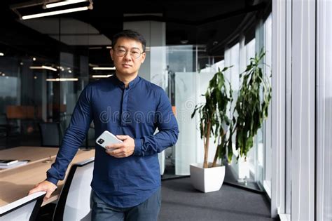 Portrait Of Serious Thinking Asian Man Inside Office Man In Glasses And Shirt Looking At Camera