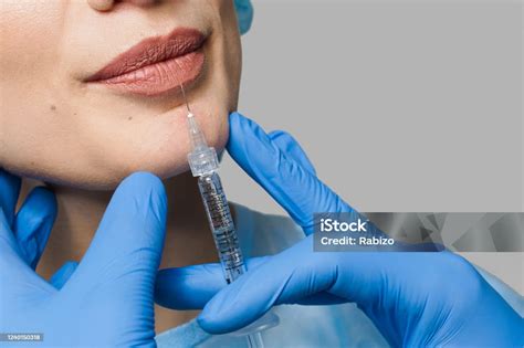 흰색 배경에 매력적인 여자를위한 클로즈업 입술 확대 주사 성형 외과 의사는 의료 클리닉에서 입술에 주사를 않습니다 화장품 젊어