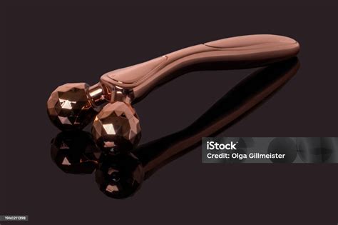 스킨 케어 도구 황금색 금속 3d 얼굴 마사지기 어두운 배경에서 더 나은 혈액 순환과 근육 활성화를 위한 안면 리프트 롤러 미용